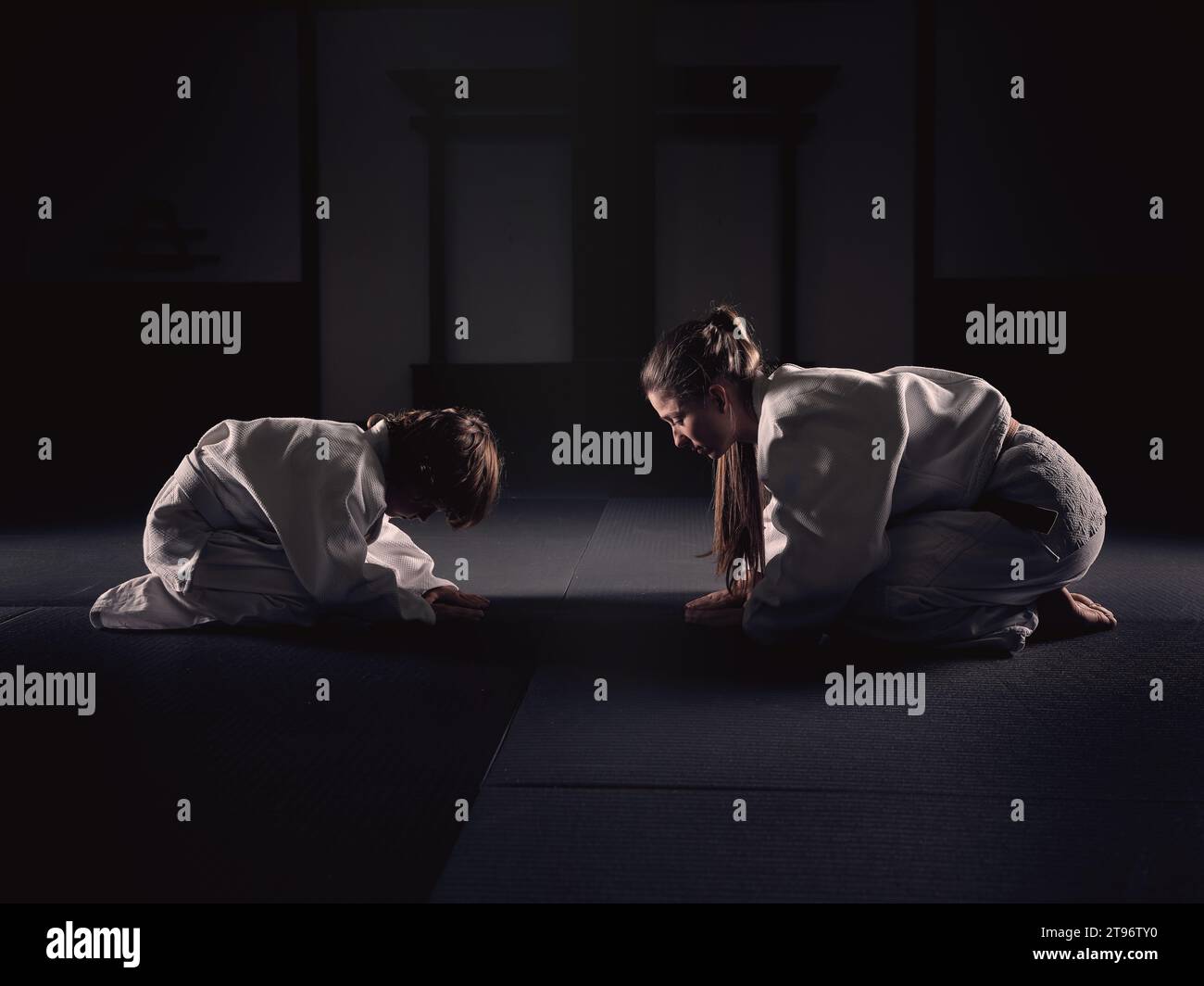 Side view of Krav Maga female instructor and kid sitting on knees in ...