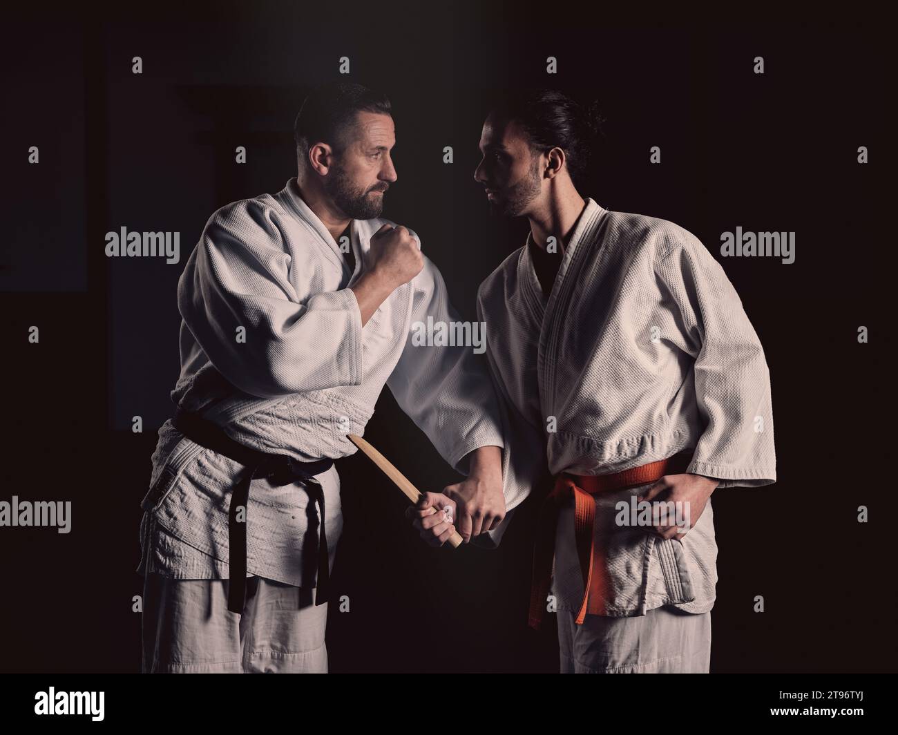Focused ethnic judo coach in judogi demonstrating self defense against ...