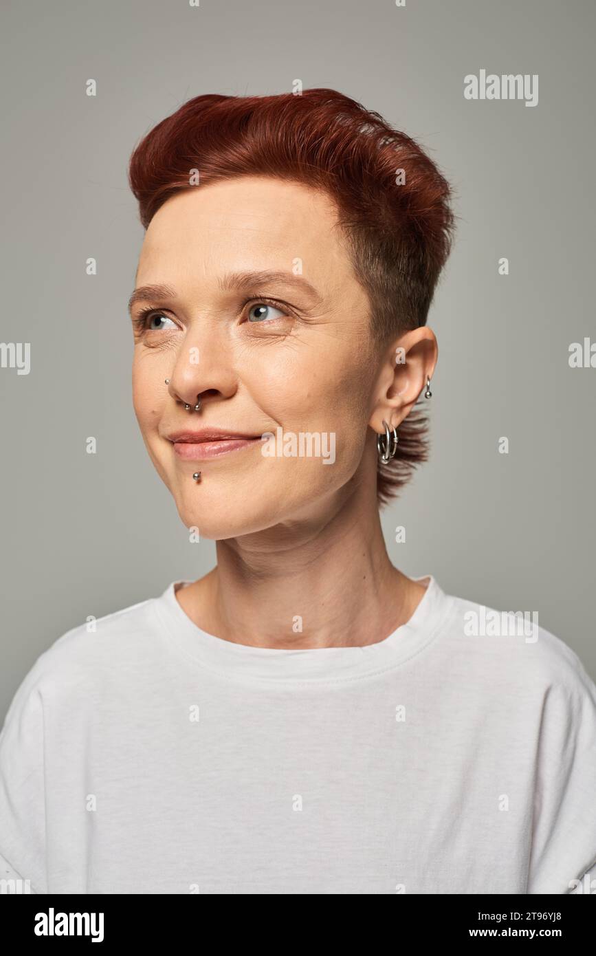portrait of redhead non-binary model with facial piercing smiling and ...