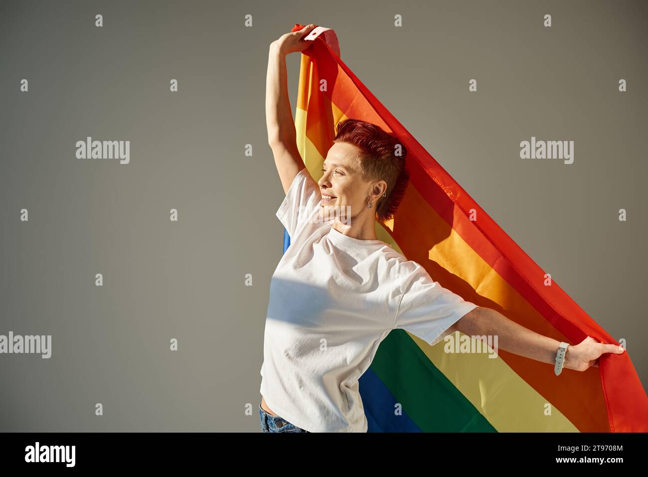 happy and unique queer person in white t-shirt posing with rainbow ...