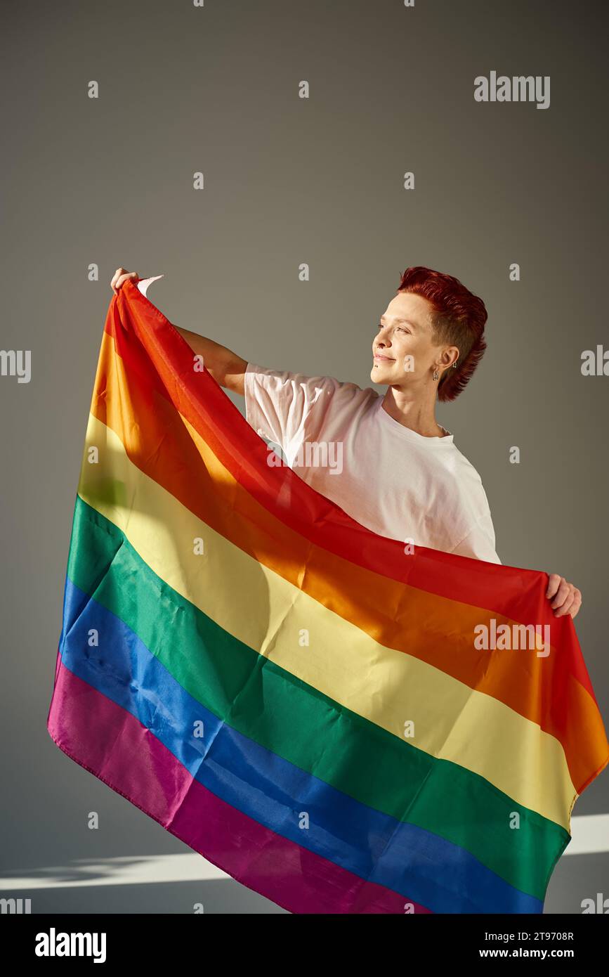 happy and unique queer person in white t-shirt posing with rainbow ...