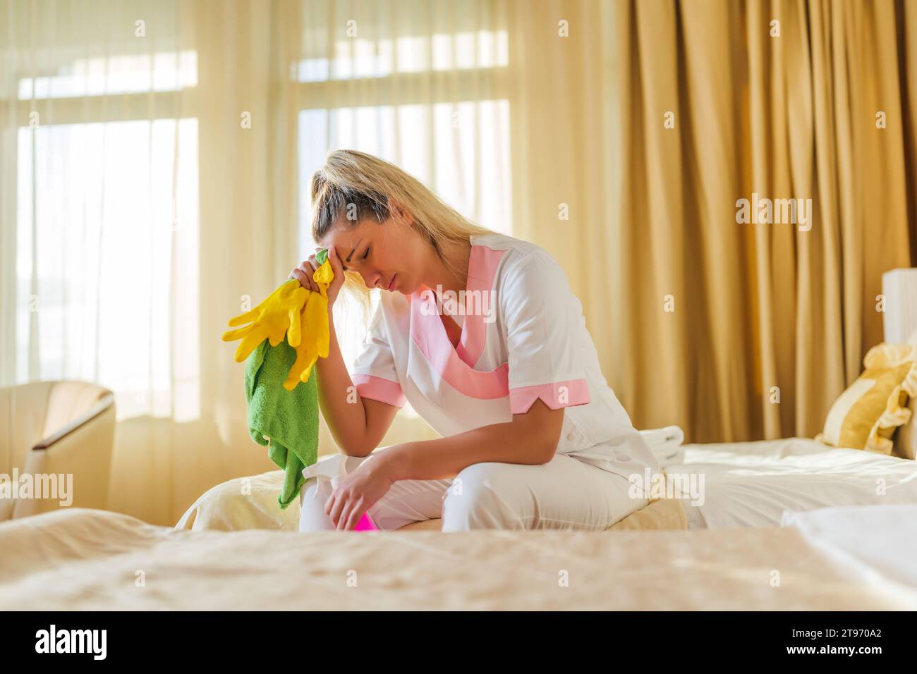 Image of sad overworked hotel maid sitting on the bed in a room Stock ...