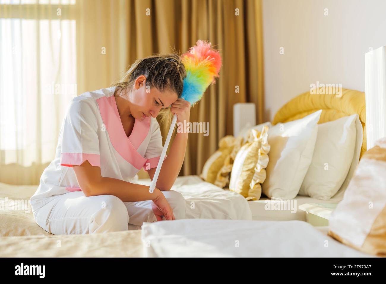 Image of sad overworked hotel maid sitting on the bed in a room Stock ...