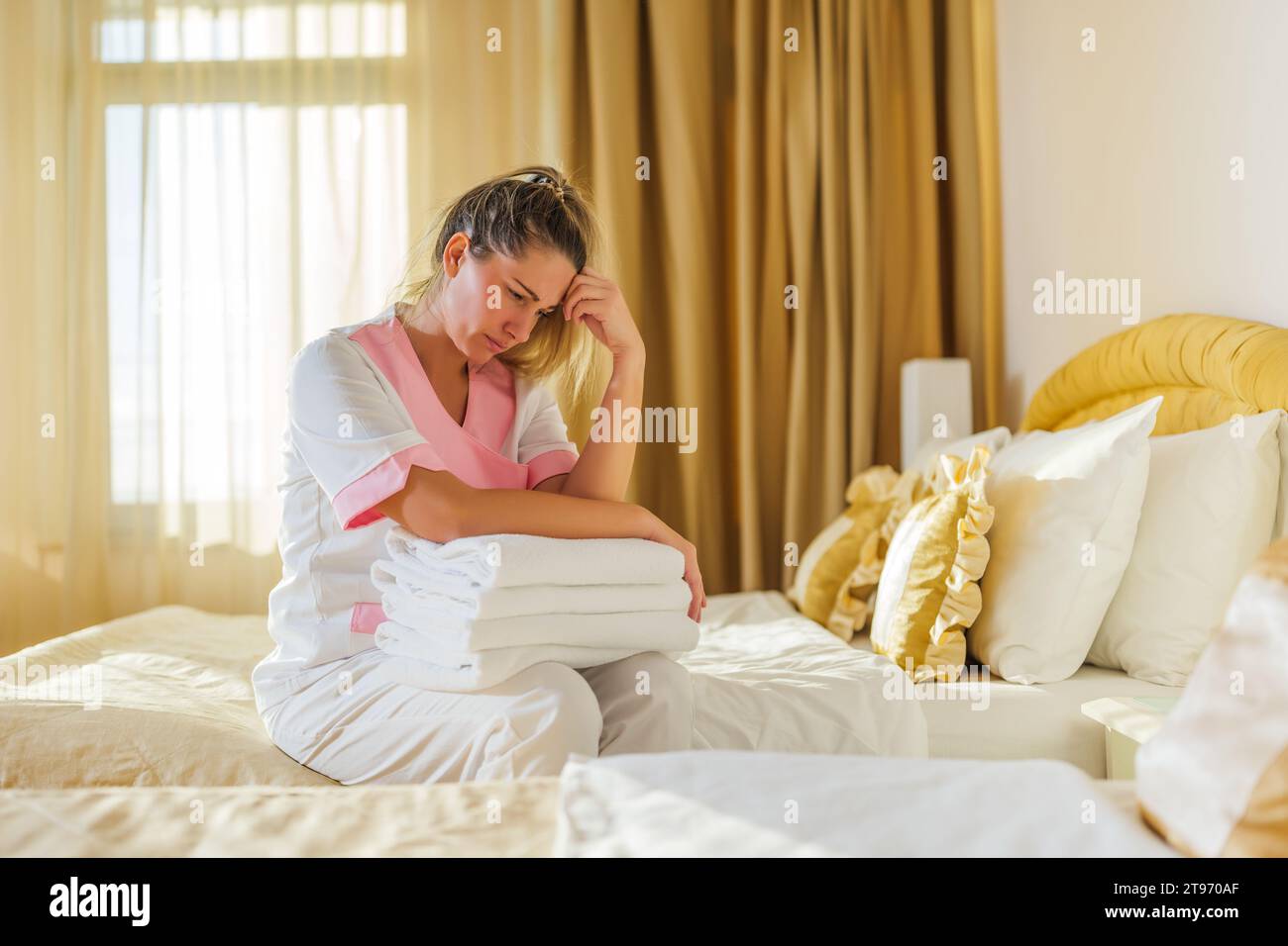 Image of sad overworked hotel maid sitting on the bed in a room Stock ...