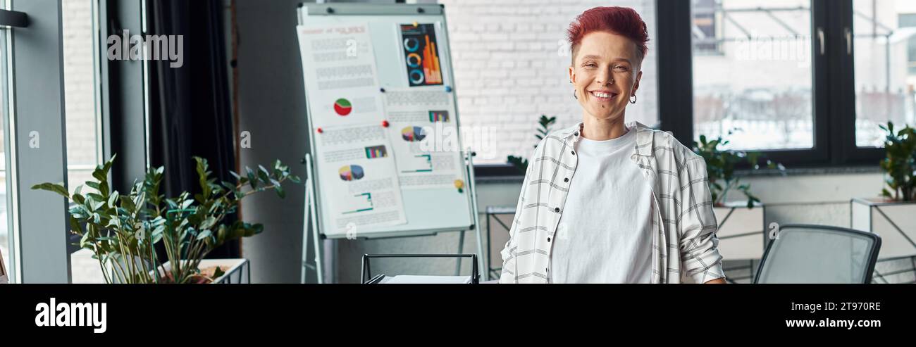 happy bigender person standing at workplace in modern office and ...