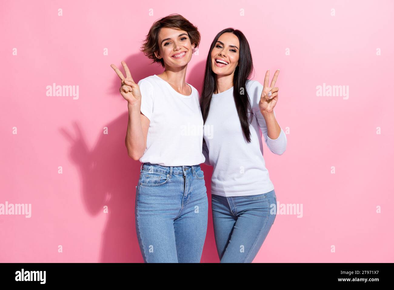 Photo of cheerful positive girls wear white stylish clothes demonstrate ...