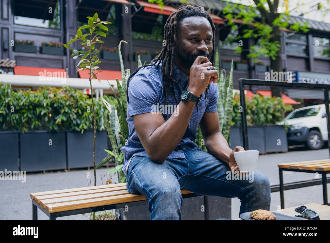 young african man with dreadlocks sitting outdoors drinking coffee and ...