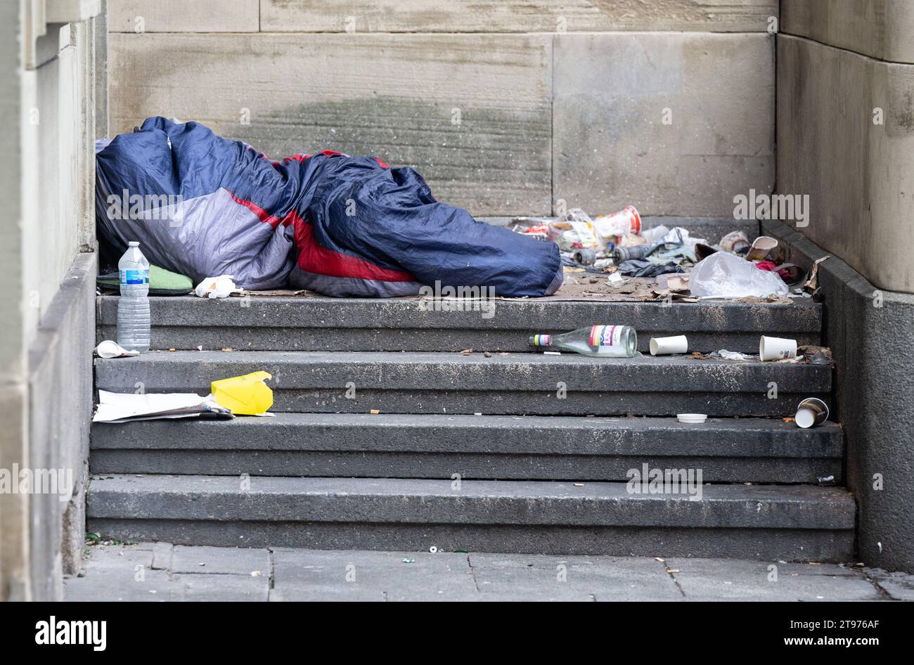 23 November 2023, Hesse, Frankfurt/Main: A homeless man lies amidst ...