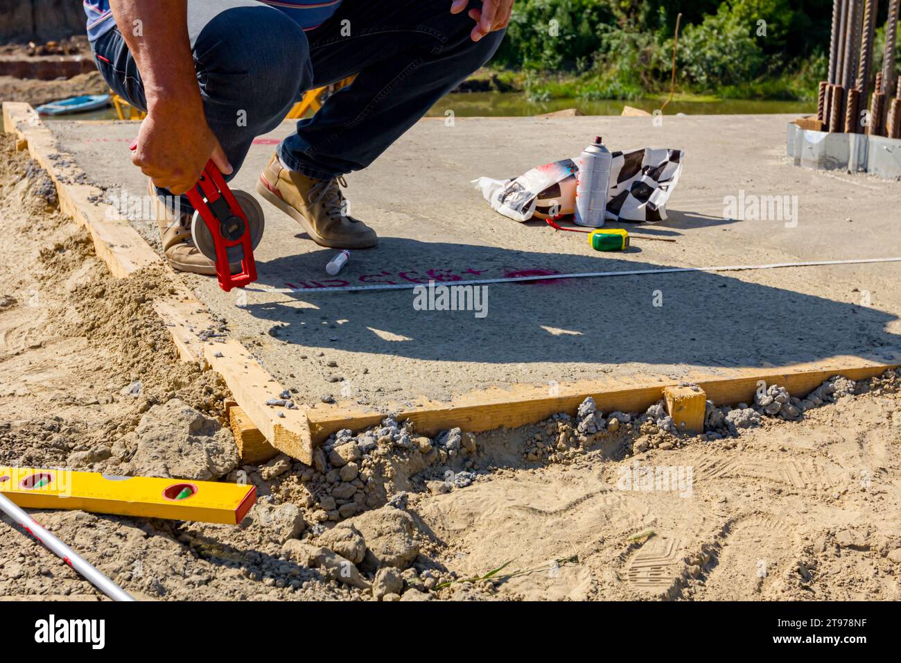 Worker in crouching position uses a land measuring tape to precise ...
