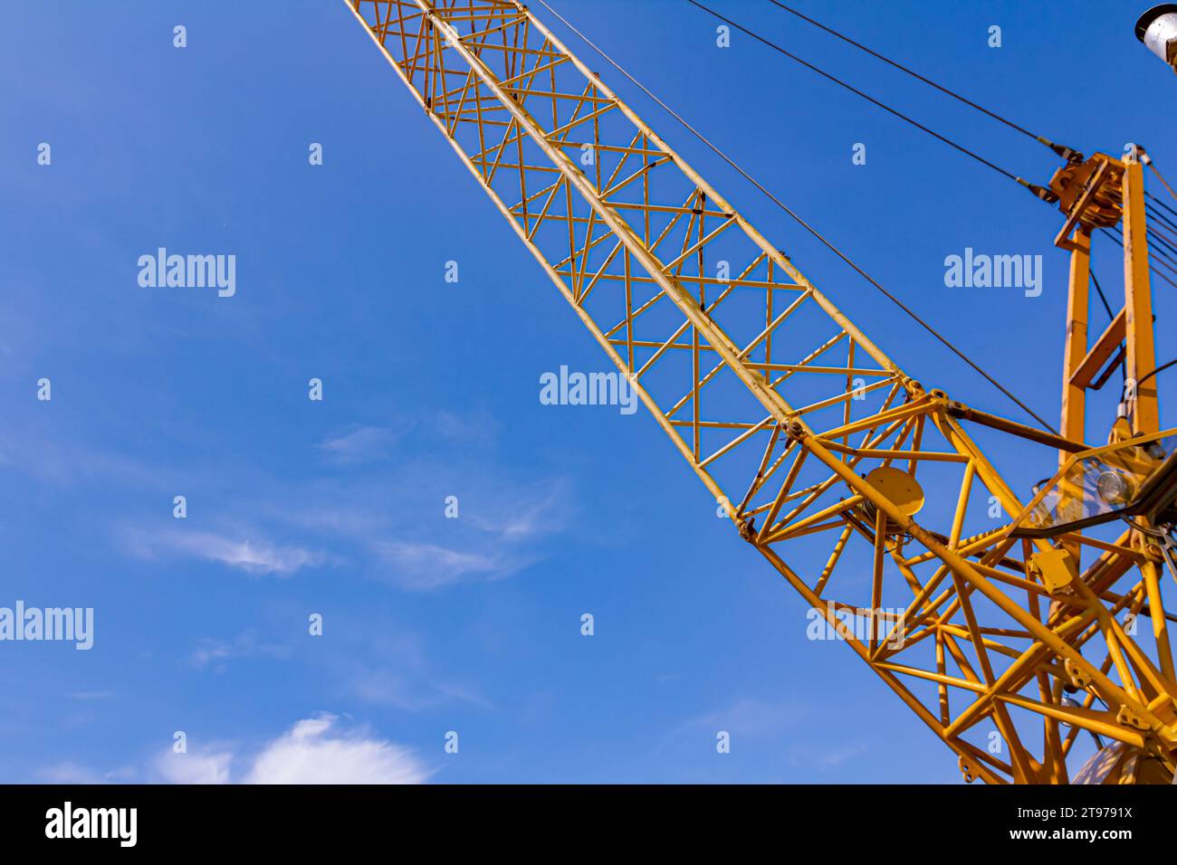 Tall yellow telescopic latticed boom of mobile crane with hoist ropes ...