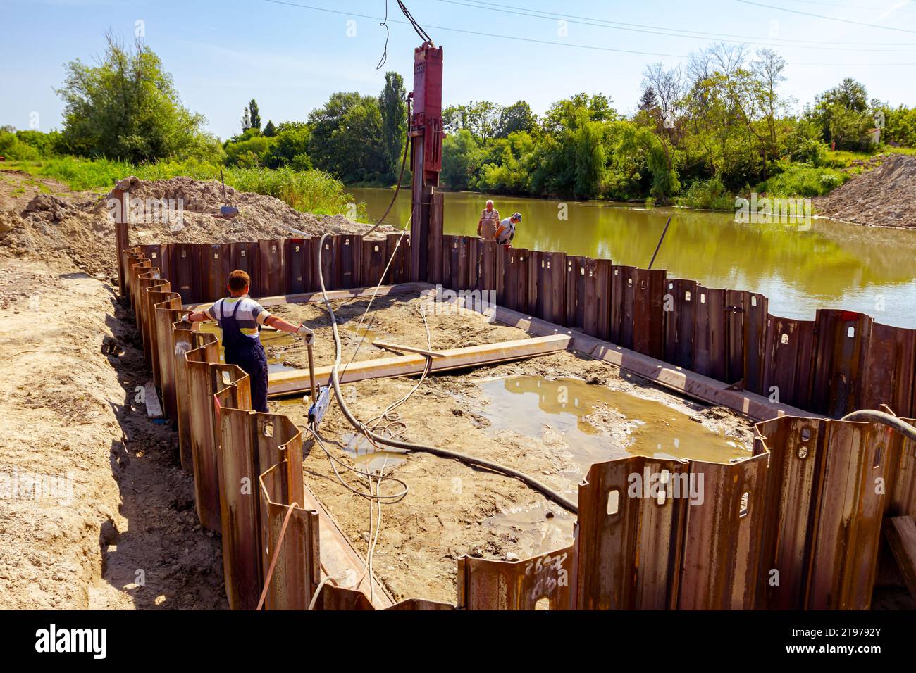 Mobile crane truck with pneumatic hammer is installing metal piles in ...