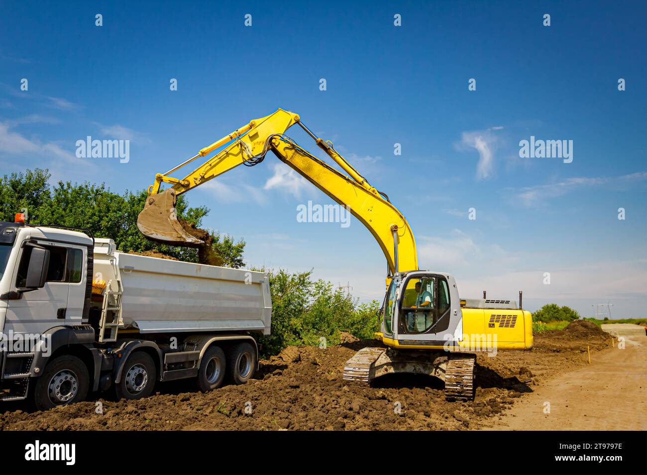 Caterpillar excavator is filling dumper truck with front bucket full of ...