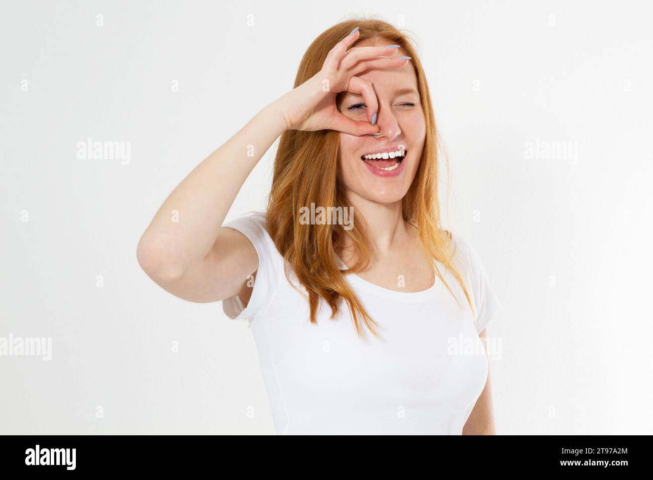 Red head girl in colorful clothing holding her fingers around the eye ...