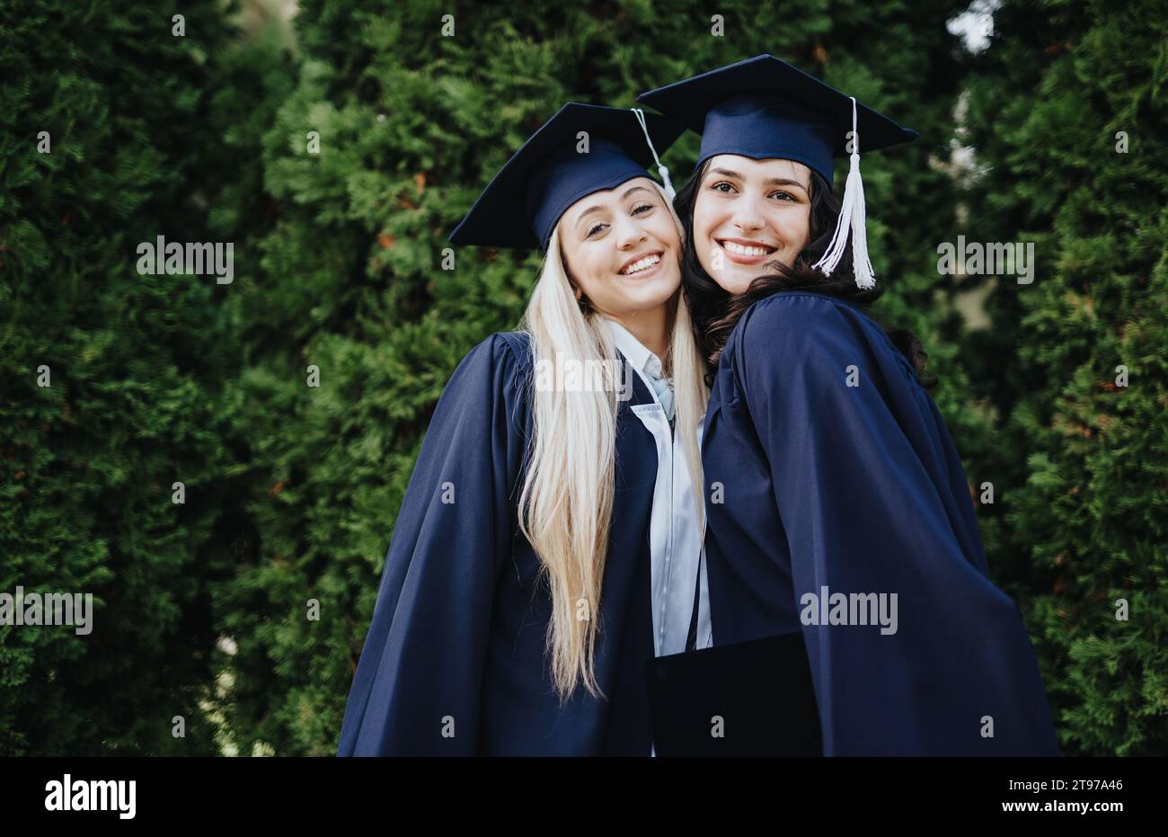 University students celebrate graduation outdoors, hugging, sharing ...