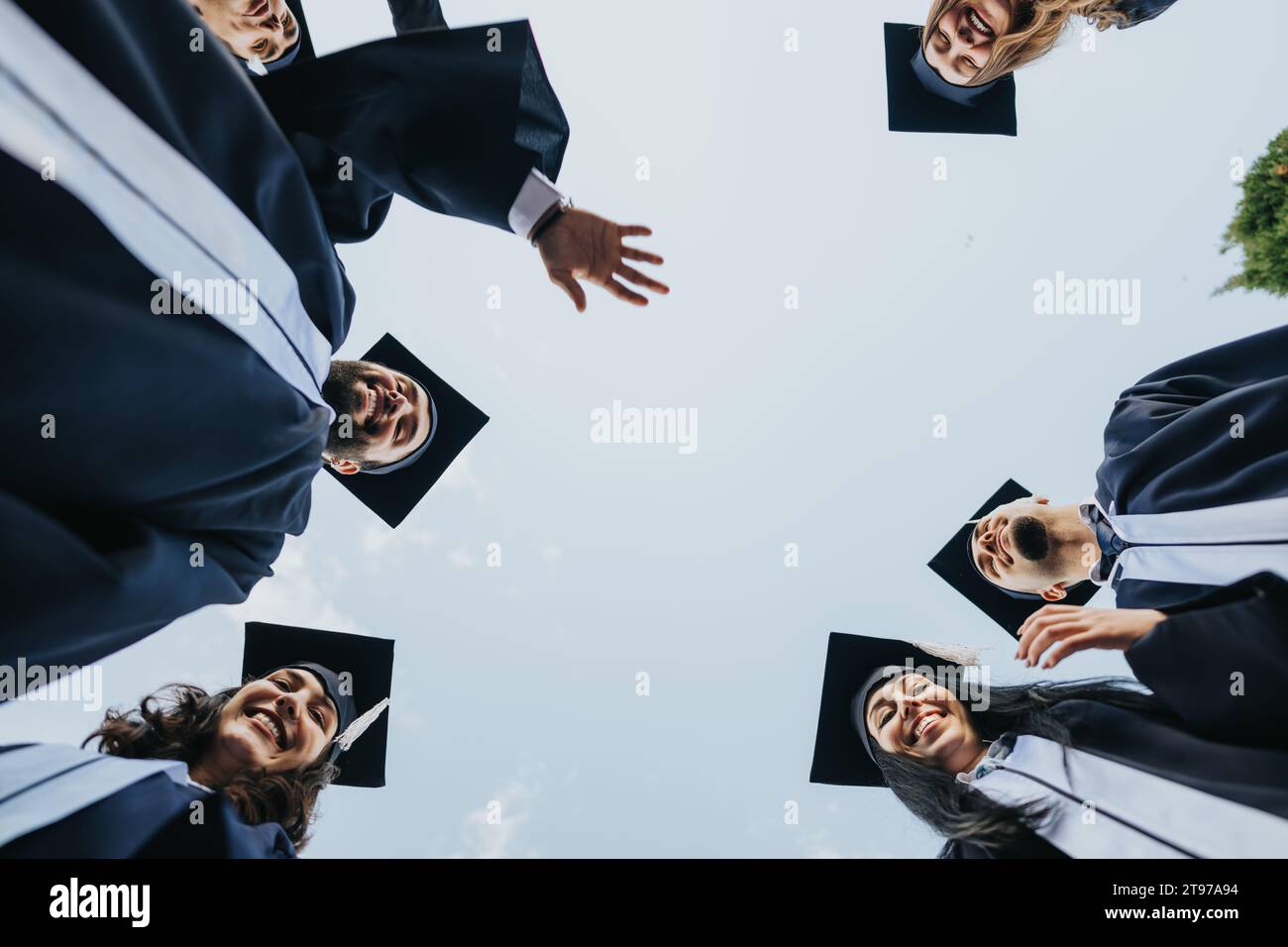 Group of students putting their hands together while standing in circle ...