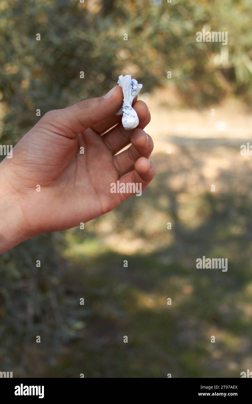 Hand, packet and drugs outdoor in forest for cocaine, recreation or ...
