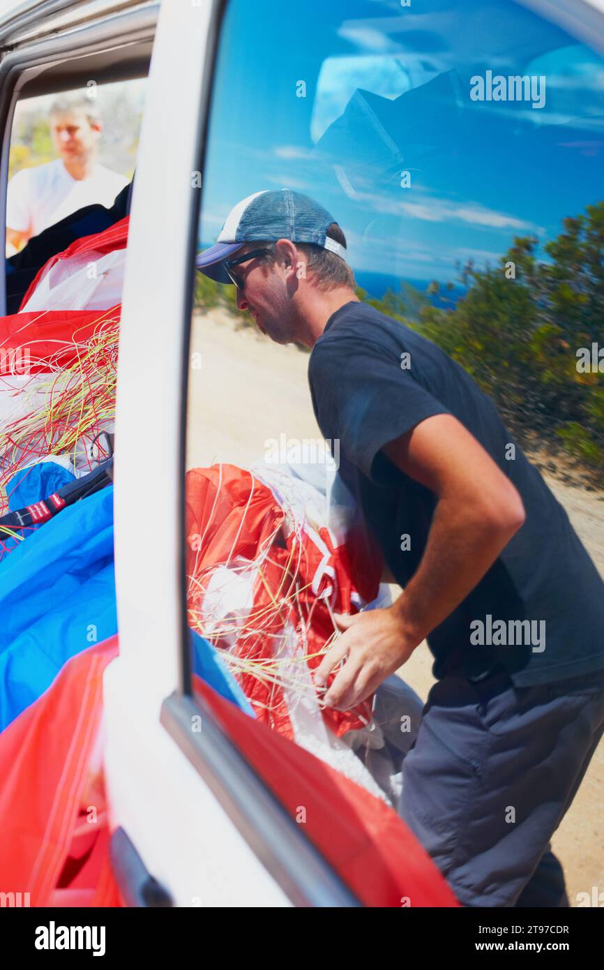 Extreme sports, adventure and a parachute in a car with a man unpacking ...