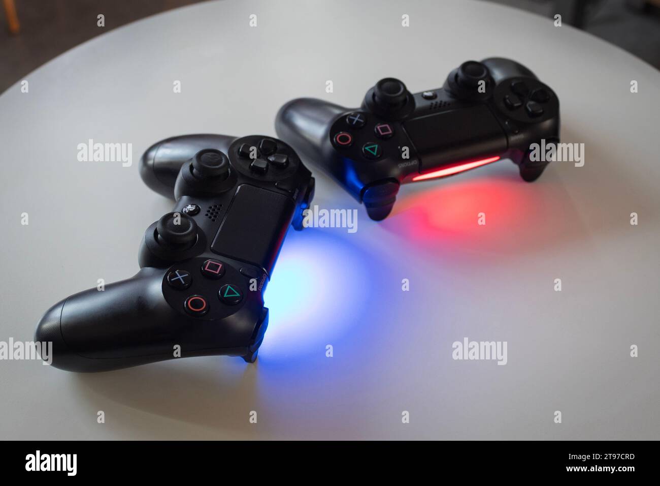 Closeup to a two Play station 4 wireless controllers over a white desk ...