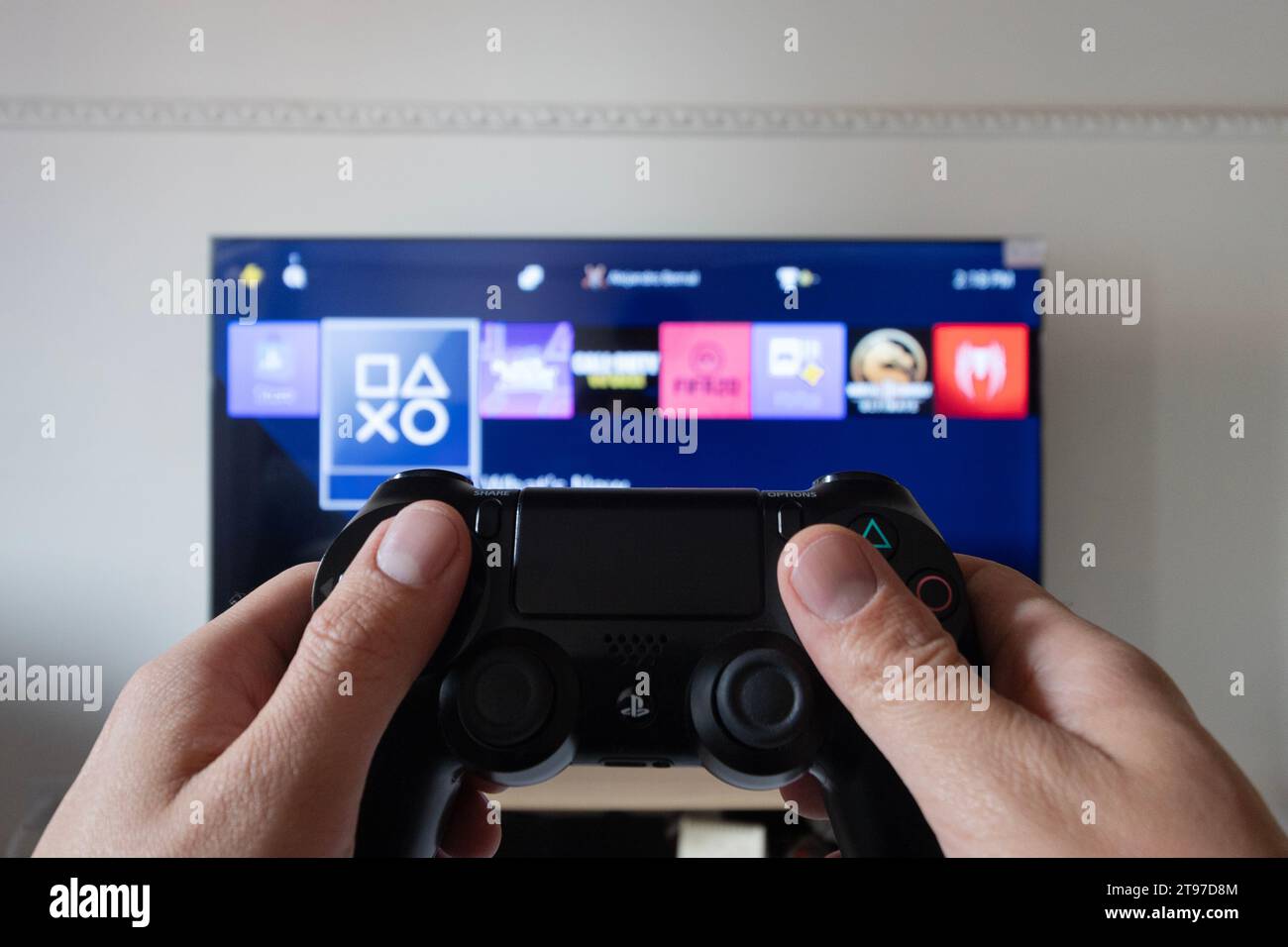 A male hand holding a play station 4 controller searching for a video ...