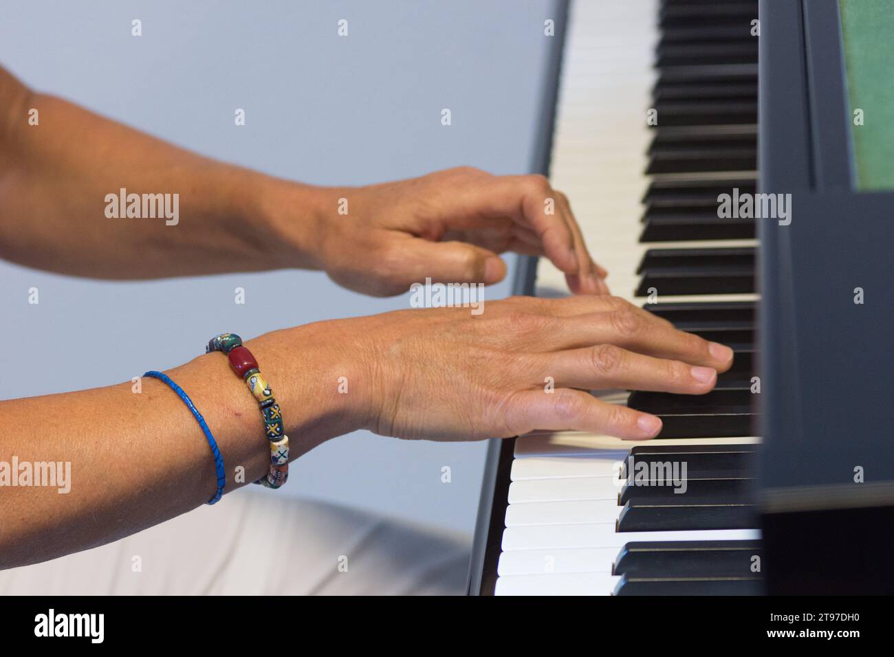 Human hands playing the keys notes and chords on a classic black piano ...