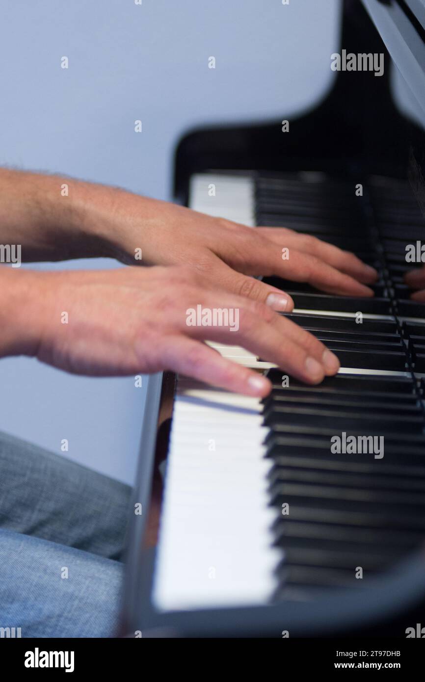 Human hands playing the keys notes and chords on a classic black piano ...