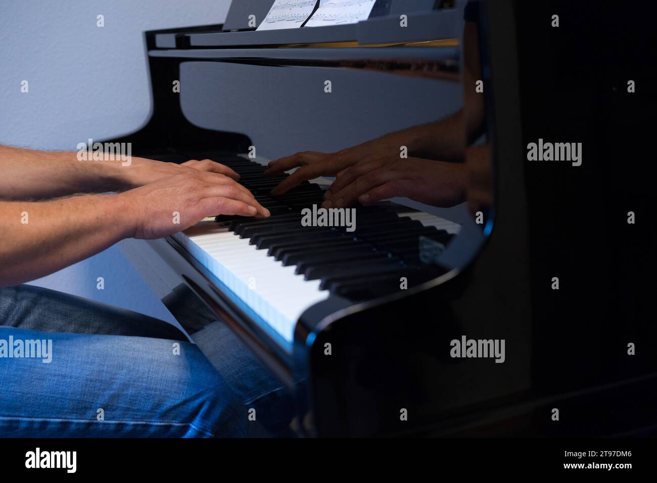 Human hands playing the keys notes and chords on a classic black piano ...