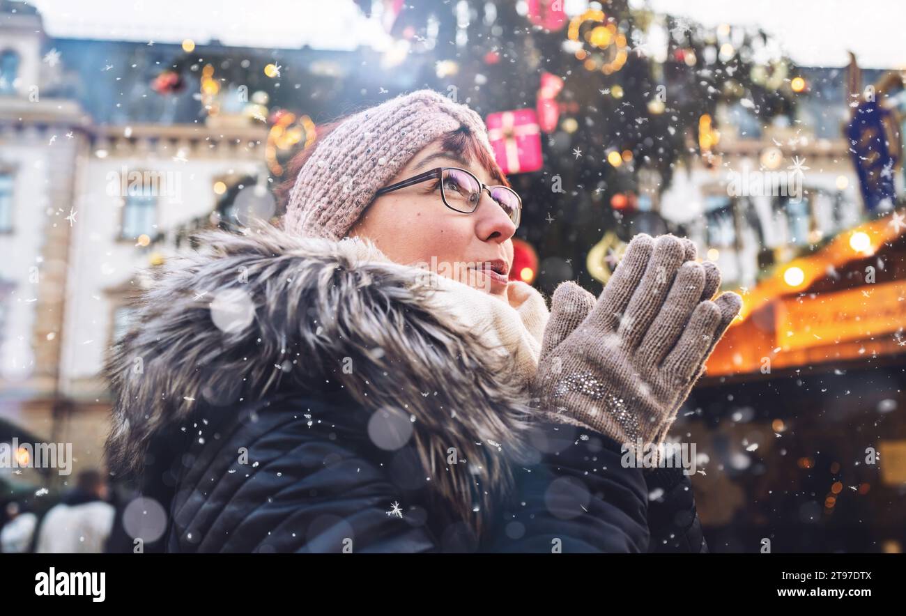 Woman with glasses and a winter hat claps hands together to warm up ...