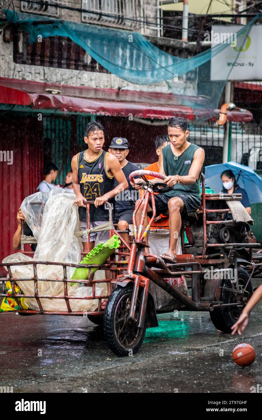 Some Filipino workers make a delivery of goods on a tractor style truck ...