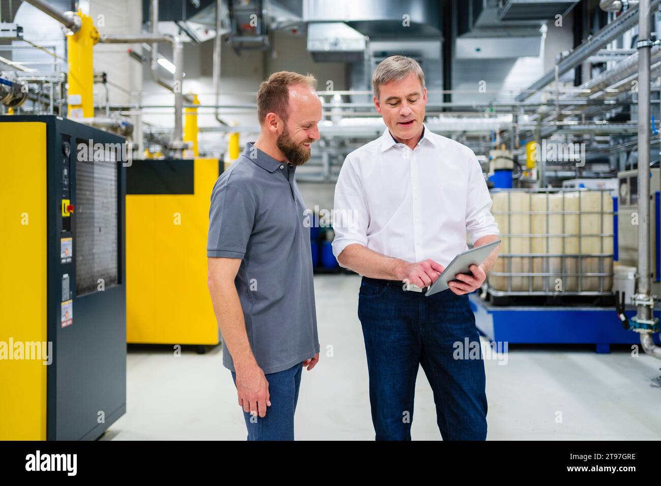 Employee and businessman with digital tablet talking in factory Stock ...