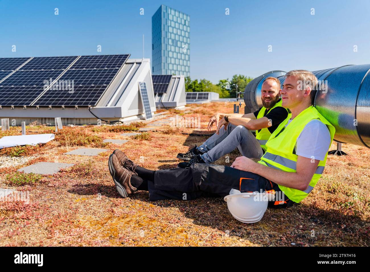 Two solar panel technicians taking a well-deserved break on the rooftop ...