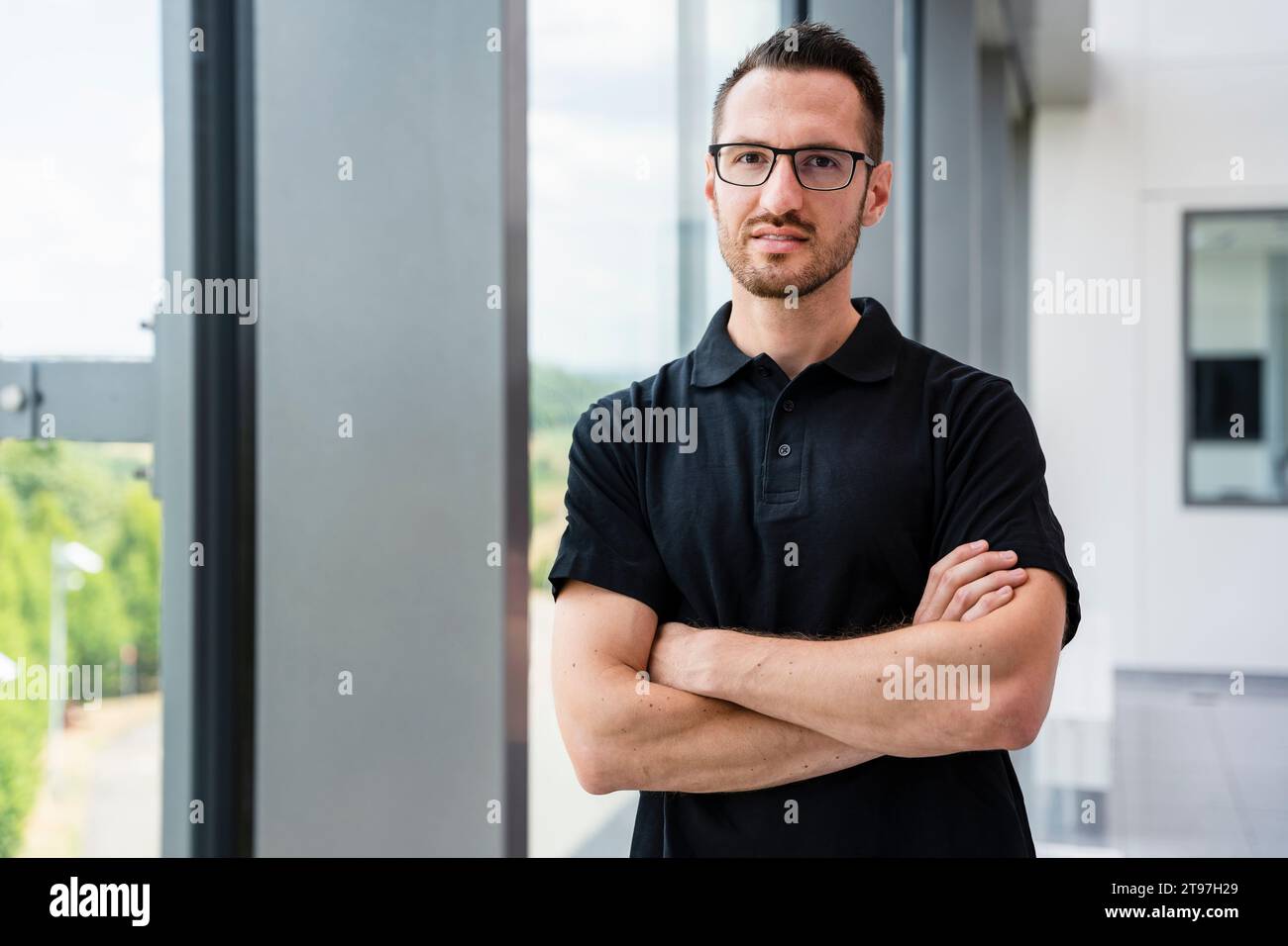 Contemplating businessman standing by window with arms crossed Stock ...