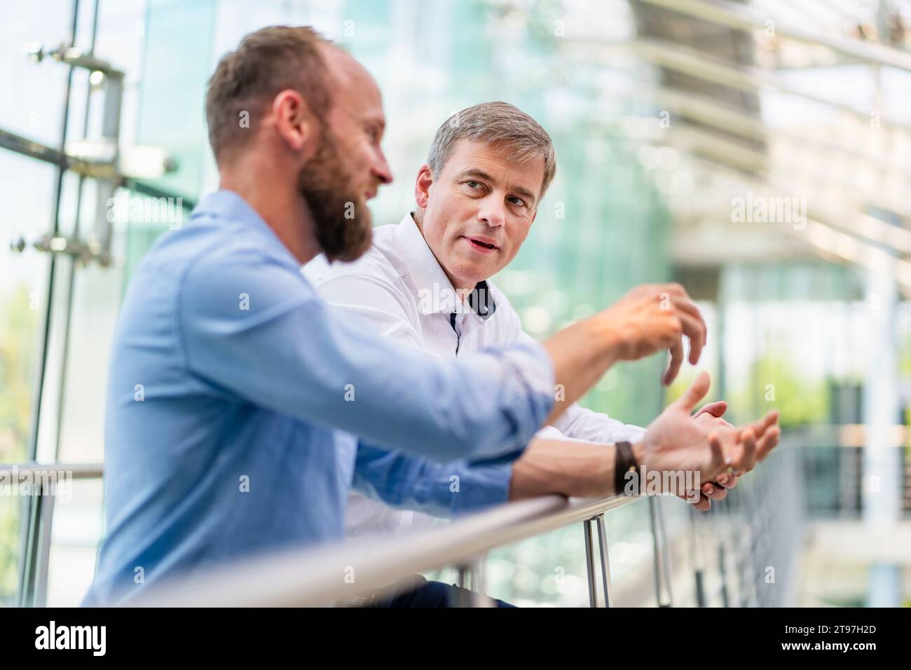 Colleagues discussing innovative business solutions leaning standing in ...