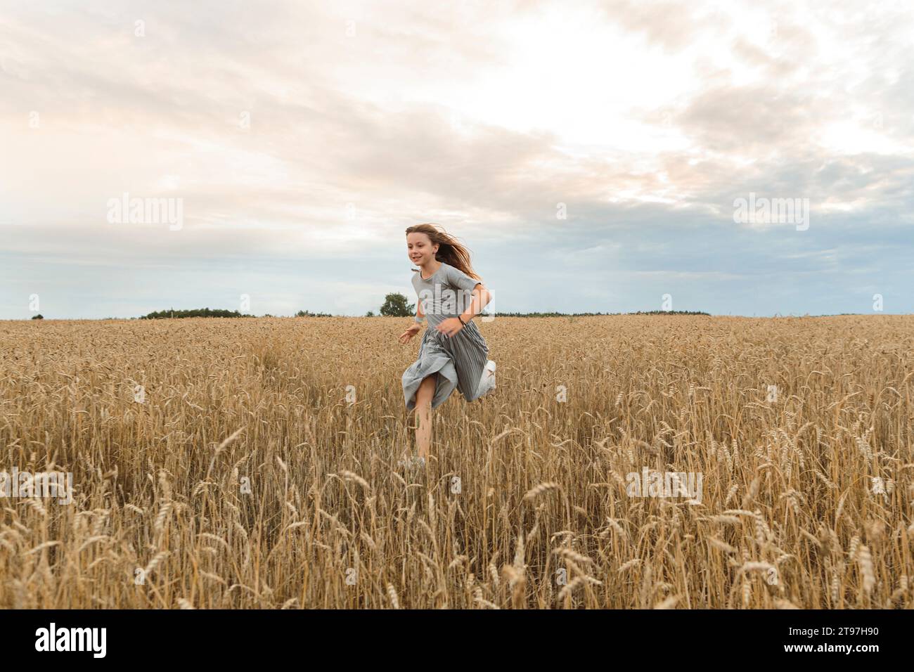 Happy girl running amidst field under sky Stock Photo - Alamy