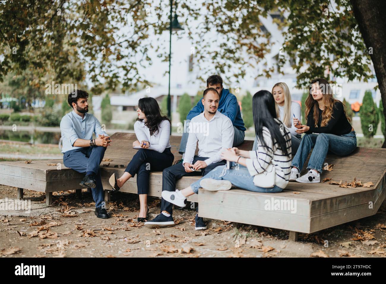 Young students discussing and collaborating in a park, working on a ...