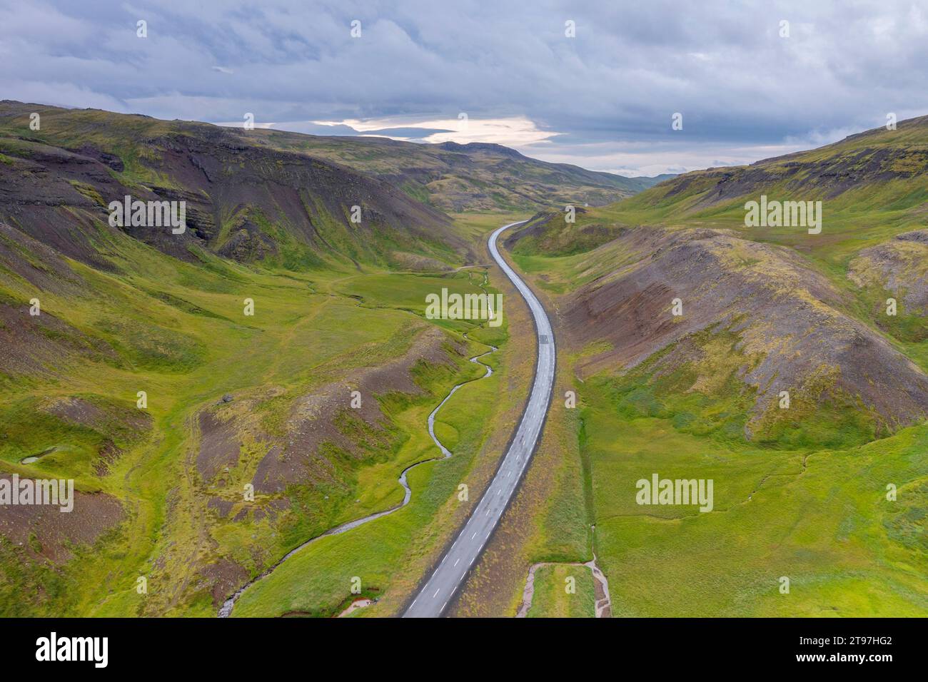 Iceland, Aerial view of remote road and stream stretching between hills ...