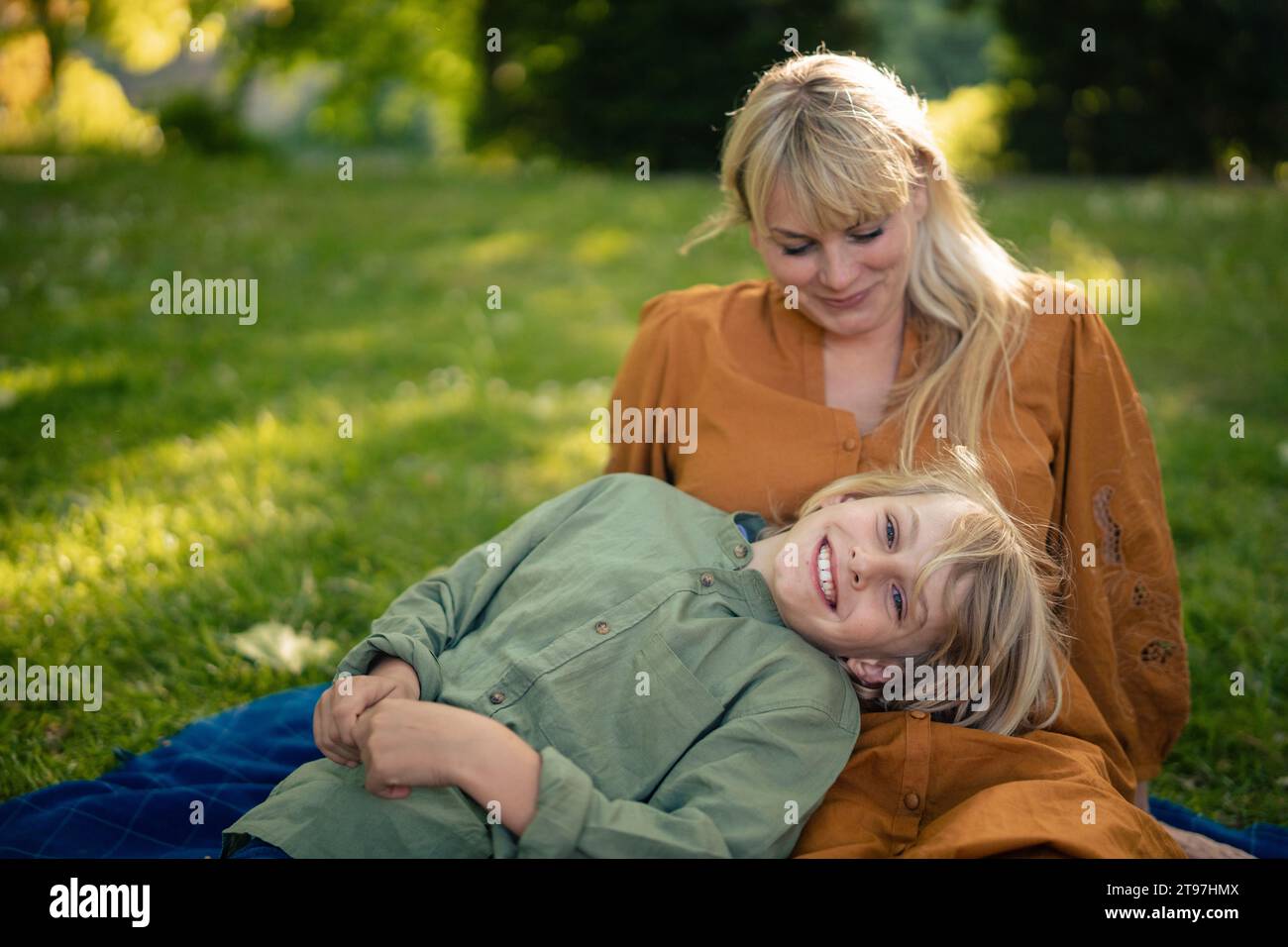 Smiling boy lying on mother's lap in park Stock Photo - Alamy