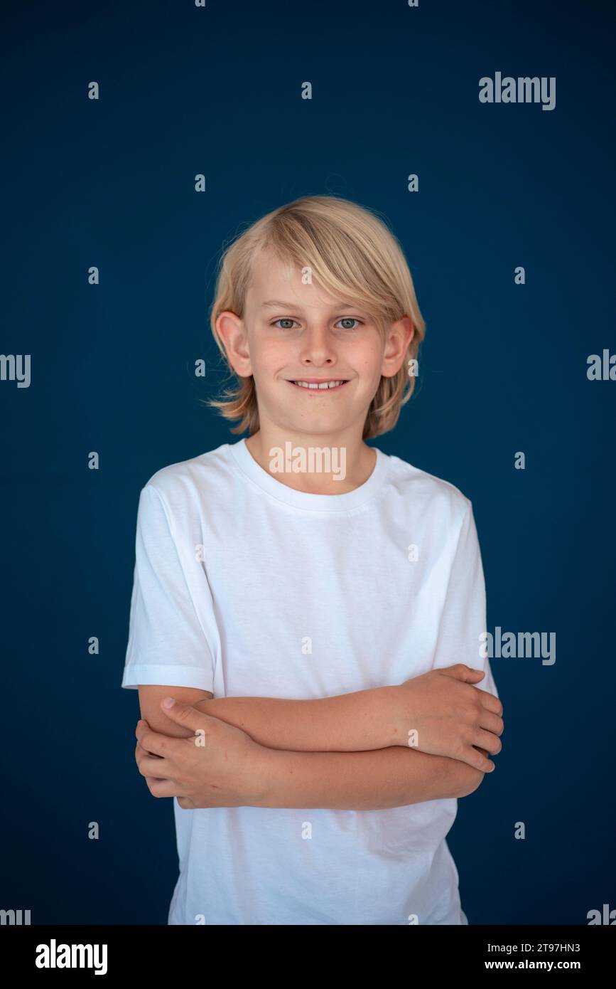 Happy boy standing with arms crossed against blue background Stock ...