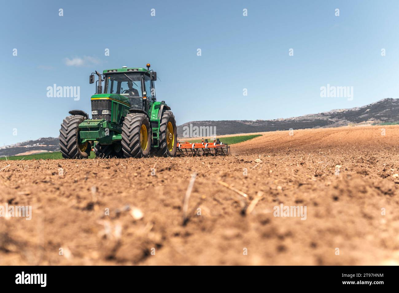 Farmer plowing field with tractor under sky Stock Photo - Alamy