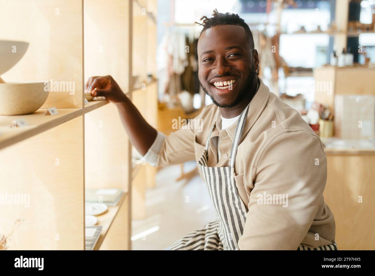 Happy owner arranging products on shelf in store Stock Photo - Alamy