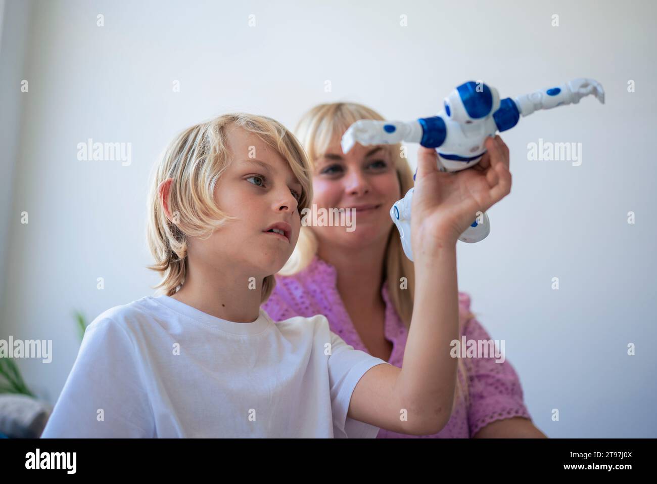 Smiling mother and son playing with robot at home Stock Photo - Alamy