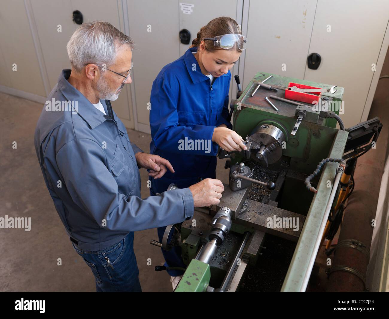 Instructor educating trainee using lathe machine at workshop Stock ...