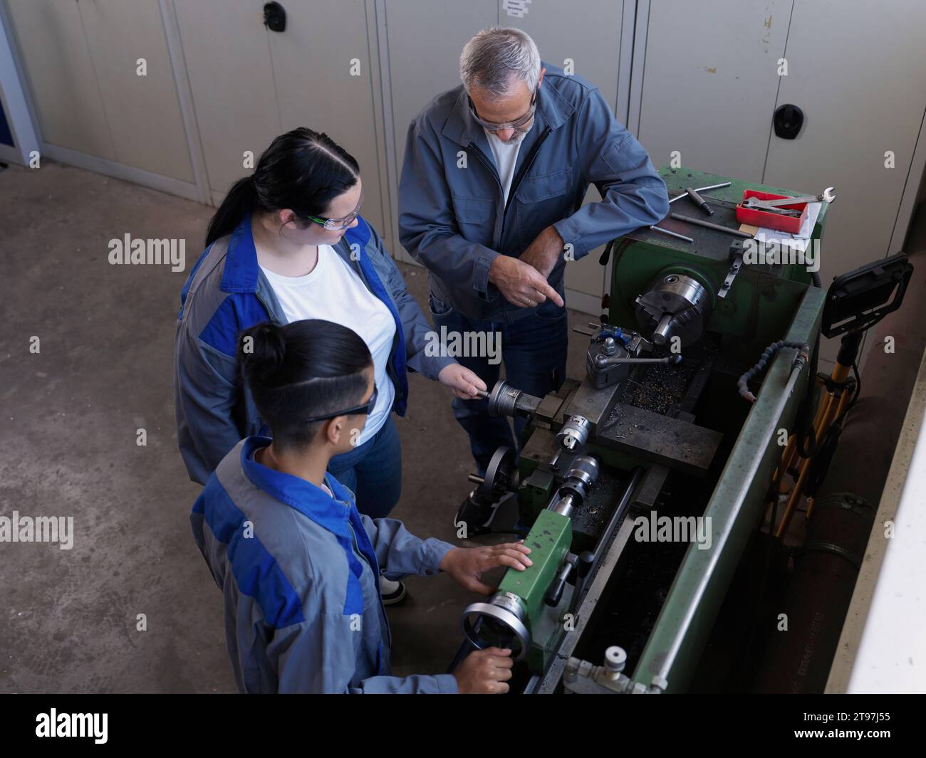 Instructor explaining lathe machine to trainees at workshop Stock Photo ...