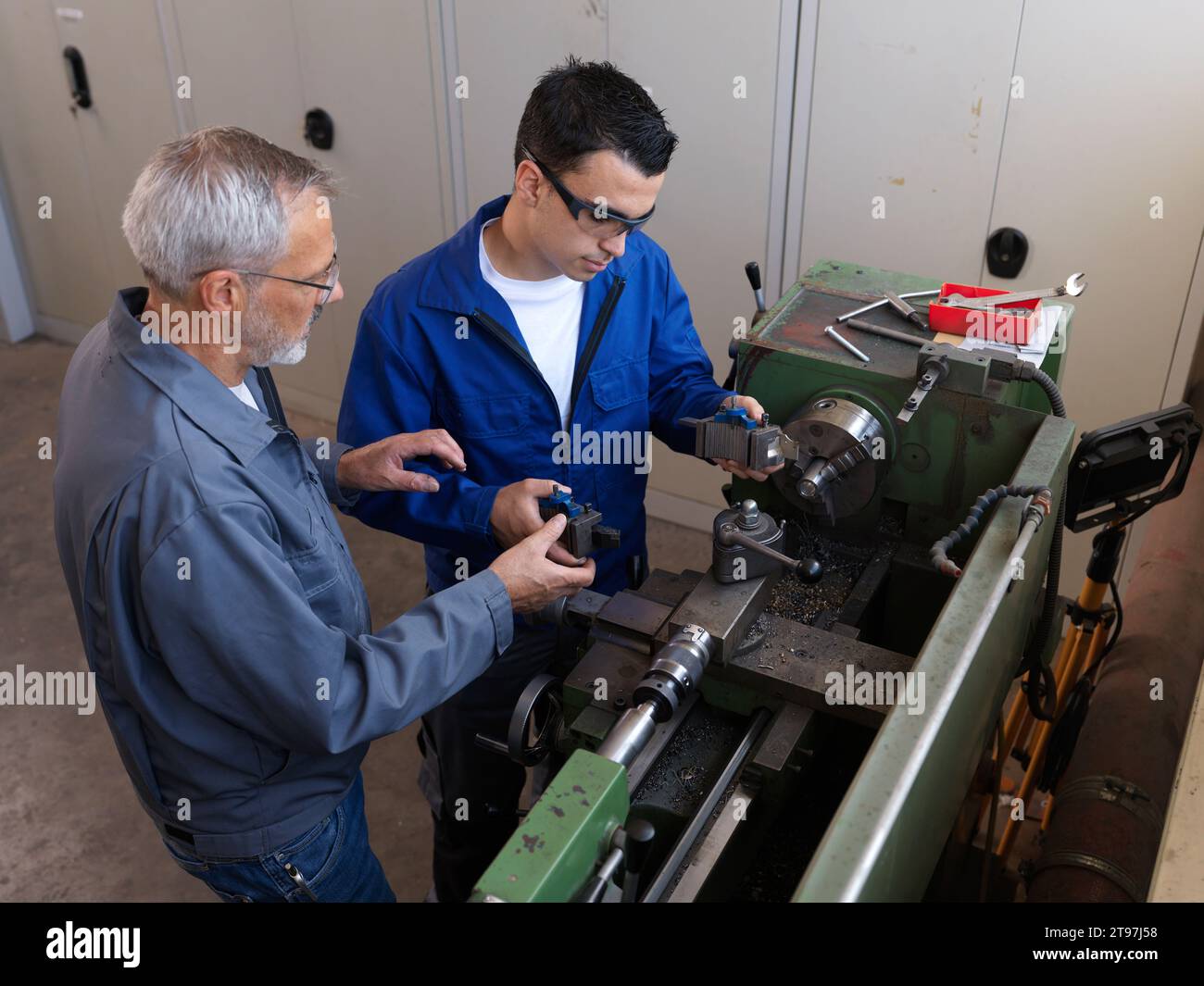 Instructor guiding apprentice using lathe machine at workshop Stock ...