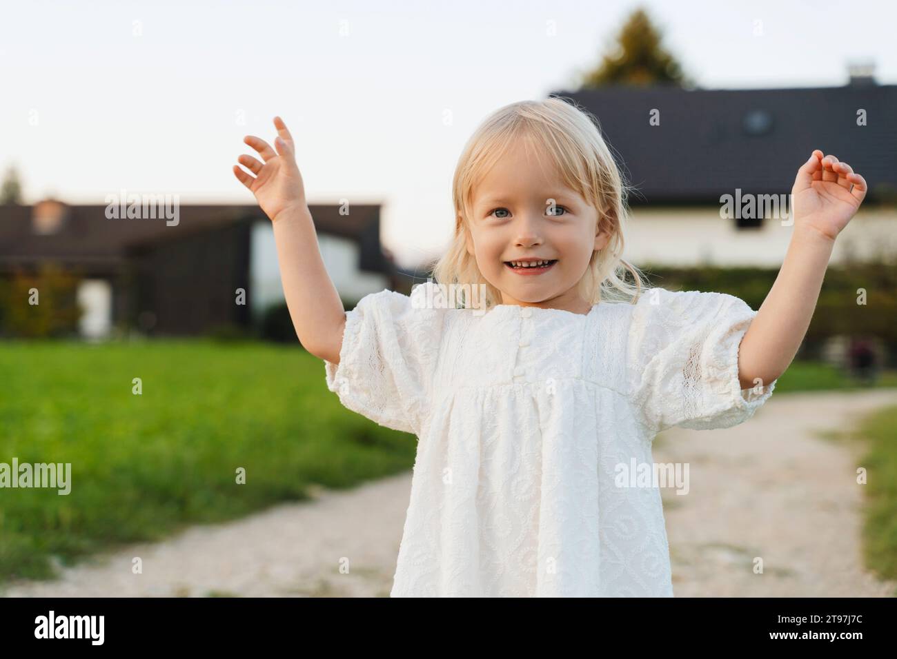 Happy girl with arms raised standing in front of houses Stock Photo - Alamy