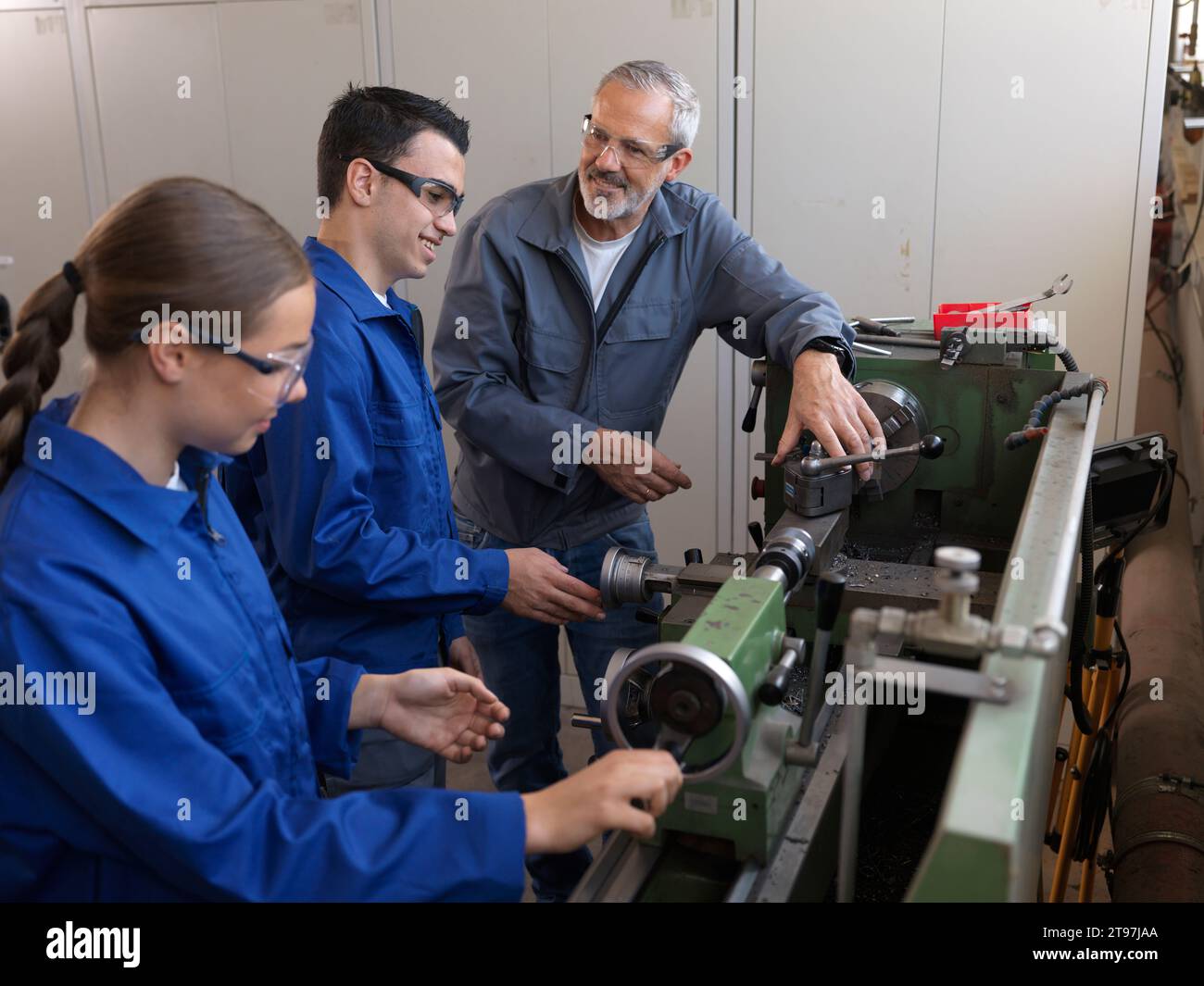 Instructor discussing with trainees over lathe at workshop Stock Photo ...