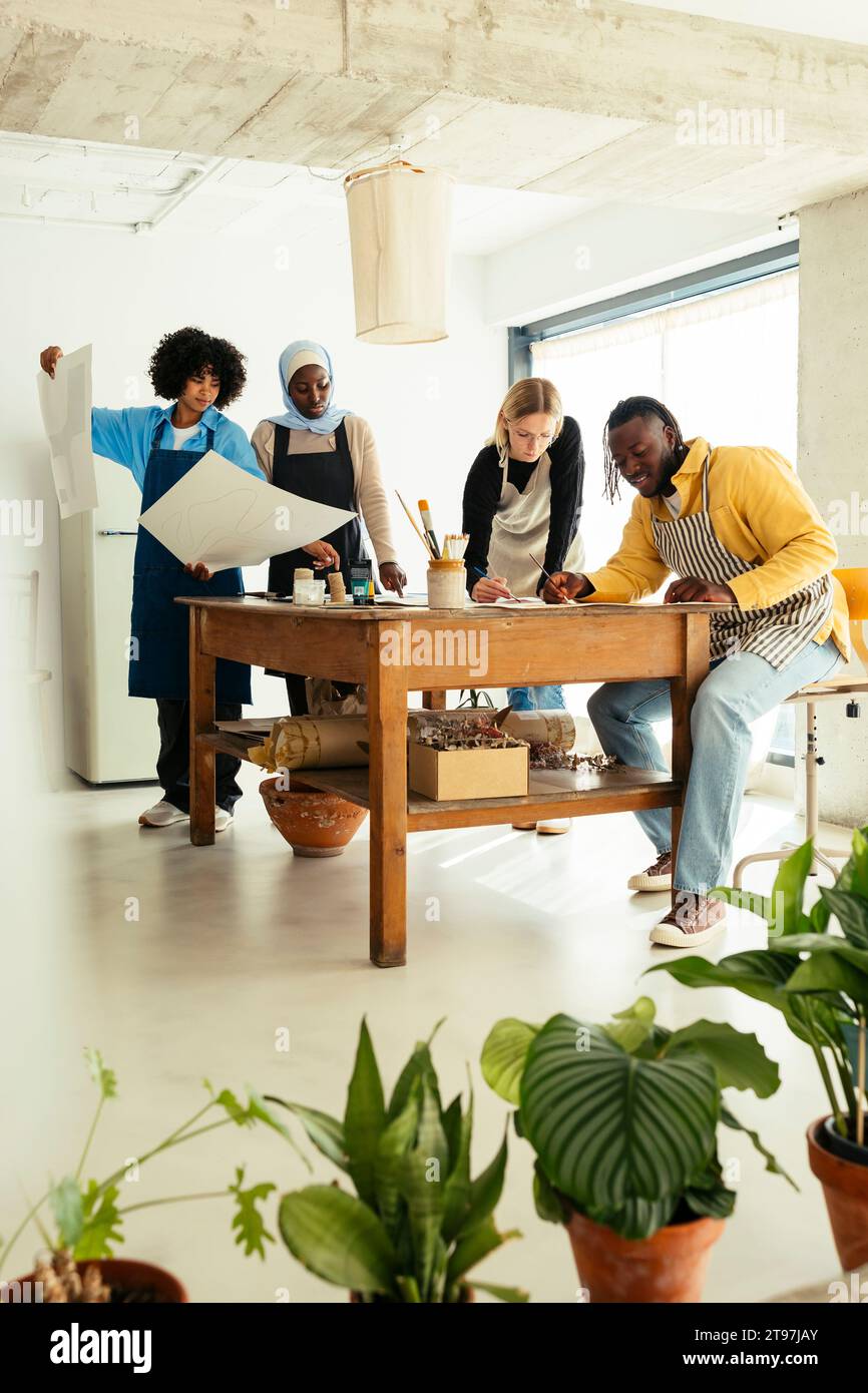 Artists comparing paintings and working at desk in studio Stock Photo ...