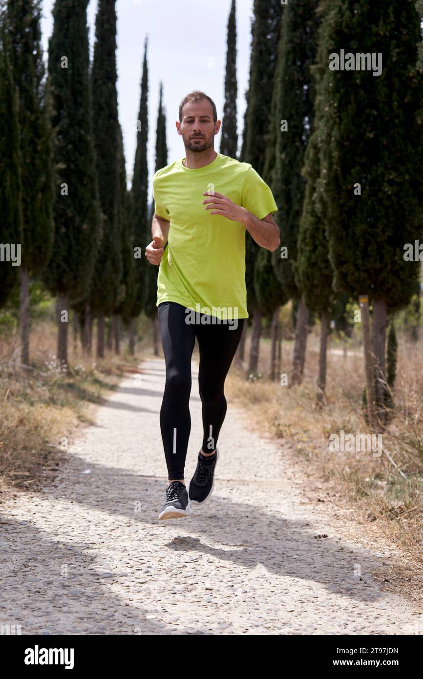 Active man running on footpath amidst trees Stock Photo - Alamy