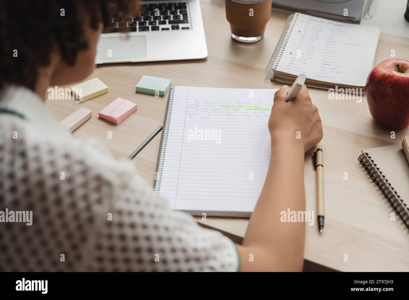 Teenage girl making notes on notepad at desk Stock Photo - Alamy