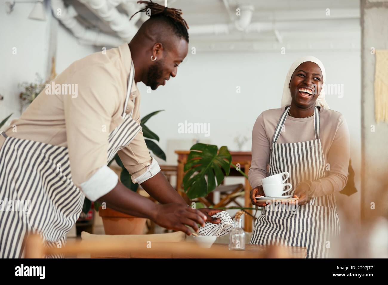 Happy baristas cleaning table and picking empty coffee cups in cafe ...