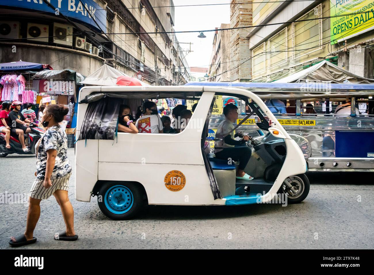 A family makes its way through the busy streets of Manila in a modern style tuk tuk style van in ...